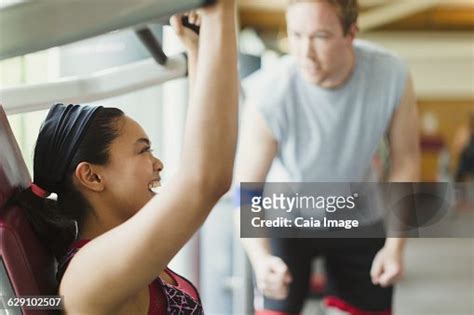 Personal Trainer Guiding Enthusiastic Woman Using Exercise Equipment At