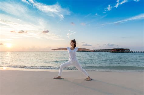 아름 다운 매력적인 아시아 여자 요가 전사 또는 일몰 몰디브에서 해변에 Virabhadrasana 포즈 연습 너무 편안한 느낌과