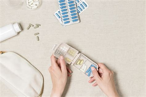 여성 손에 오픈 베이지 색 플라스틱 용기에 캡슐과 정제를 볼 수 있습니다 섬유 테이블에 비타민과 의약품의 매일 섭취를위한 알약 상자 아름다움과 건강 의료를 위한 라이프스타일