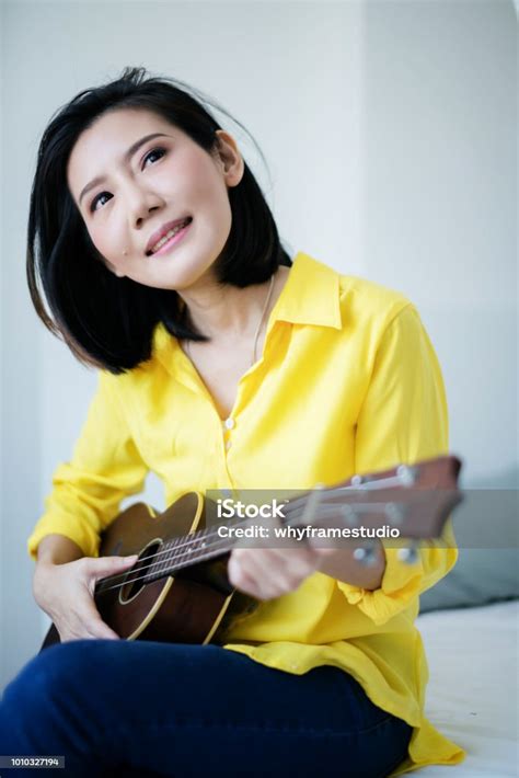 취미 음악 Ukelele 행복 순간 노란색 셔츠에 아름 다운 아시아 여자와 노래 하 고 침대 화이트 룸 배경에서 Ukulel를 재생 귀여운에 대한 스톡 사진 및 기타 이미지