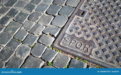 Cast Iron Manhole Cover With SPQR Engraving On A Stone Floor With A Geometric Design Editorial