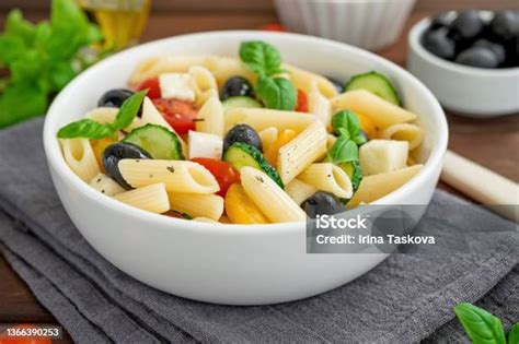 토마토 오이 붉은 양파 올리브 치즈를 곁들인 건강한 파스타 샐러드를 어두운 나무 배경에 그릇에 담습니다 공간을 복사합니다 0명에