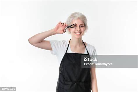 흰색 티와 검은 앞치마에 예쁜 젊은 헤어 스타일리스트는 흰색 배경 위에 고립 된 서 작업에 대한 준비가 얼굴에 가까운 검은 가위를 들고 T 셔츠에 대한 스톡 사진 및 기타