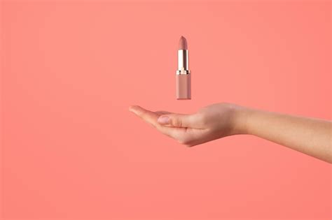 Mano femenina con lápiz labial desnudo equipo para maquillage