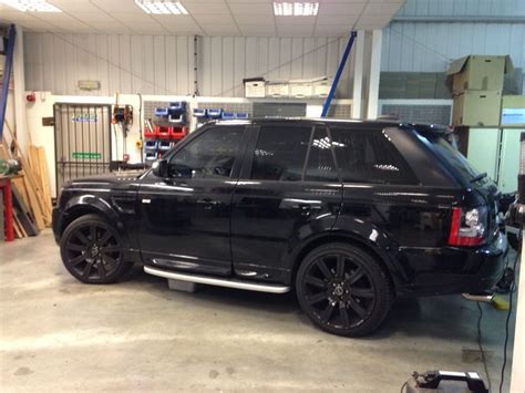 An Suv Is Parked In A Garage With Other Cars And Tools On The Wall