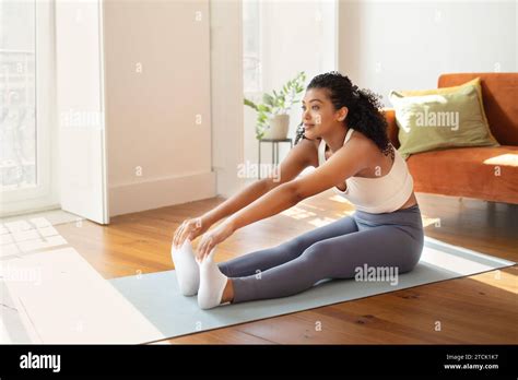 Woman Stretching On Mat Performing Seated Toe Touch Exercises Indoor