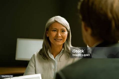 친절한 매력적인 비즈니스 우먼은 전경에 등을 대고 앉아있는 사업가와 의사 소통합니다 성숙한 회색 아시아 여자 비즈니스 사람들은