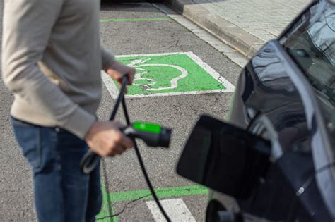 공공 충전소에서 전기 자동차에 플러그를 꽂는 알아볼 수 없는 남자의 클로즈업 45 49세에 대한 스톡 사진 및 기타 이미지 45 49세 거리 건축물 Istock