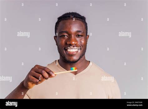 Afrian American Man Holding Colorful Rainbow Toothbrush In Gray