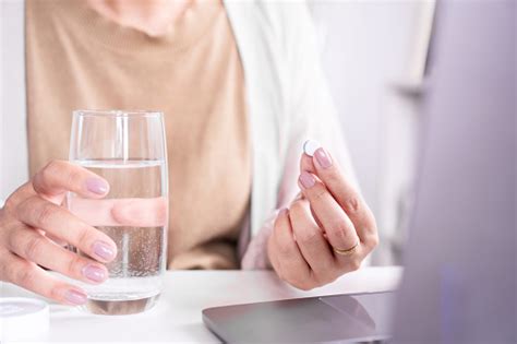 두통 감기 및 독감을 완화하기 위해 물 한 잔과 함께 파라세타몰 약을 복용하는 여자 손 A형 인플루엔자 바이러스에 대한 스톡