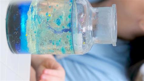 Girl With Pleasure And Joy Looks Into Bottle With Bubbles She Rubs Eyes Eyes Are Tired She Is