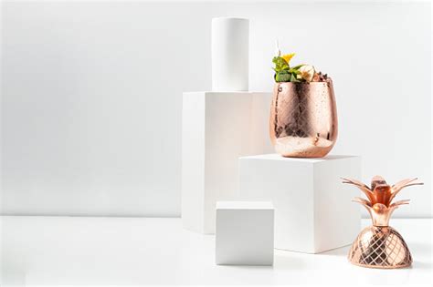 구리 스탠드의 구리 유리에 과일 딸기 및 작은 얼음을 곁들인 여러 종류의 럼에 티키 칵테일 칵테일은 흰색 바탕에 석고 인물 중 석고 인물 위에 서 있습니다 0명에 대한 스톡