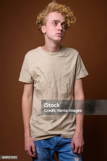 배경색에 대 한 캐주얼 옷을 입고 곱슬 금발 머리 젊은이의 스튜디오 샷 20 24세에 대한 스톡 사진 및 기타 이미지 20 24세 가냘픈 갈색 배경 Istock