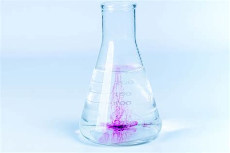 Laboratory Assistant In Gloves With A Flask And Pipette Working At The Table Flip
