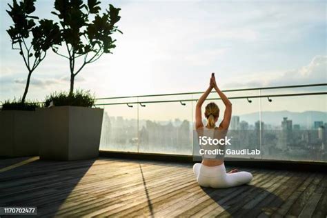 옥상에서 명상 야외명상을 위한 영적 연습 중에 휴식을 취하는 트랙수트에 있는 여성의 뒷모습 요가 포즈에 앉아 있는 활동적인