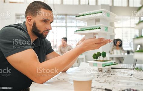 3d 모델을보고 젊은 건축가 건축 프로젝트를 계획하는 전문 건축가 건물 모델을 들고 집중된 디자이너 그의 사무실에서 일하는 기업