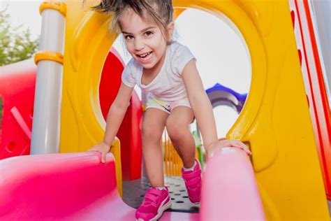 Premium Photo Portrait Of Smiling Girl On Yellow Slide In Playground