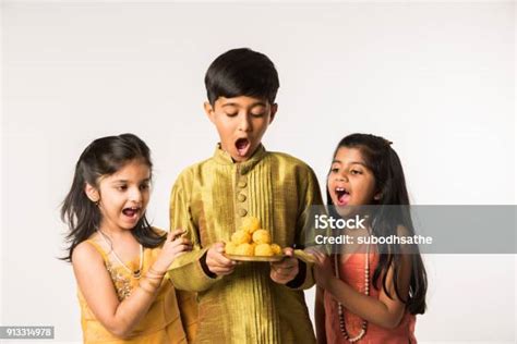 3 인도 애 들 이나 소파 또는 흰색 배경에 앉아 전통적인 착용에 형제 자매 선물 하 고 과자 나 Laddu 아이에 대한 스톡 사진 및 기타 이미지 Istock