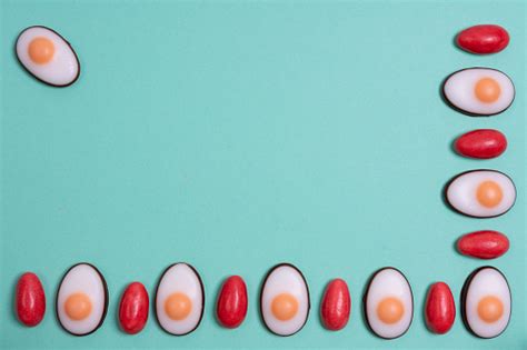 작은 빨간 부활절 달걀은 아쿠아 멘테 표면에 노른자와 달걀 흰자로 디자인 된 부활절 사탕과 교대로 배열 0명에 대한 스톡 사진