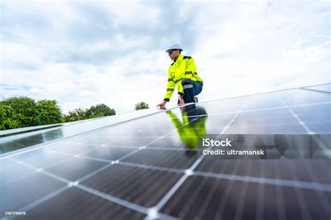 숙련된 기술자가 옥상에 설치된 태양 전지판을 조정하여 지속 가능한 에너지로의 전환을 강조합니다 안전 장비를 착용한 작업자는 재생 에너지 설비에서 정밀성을 보여줍니다 건설