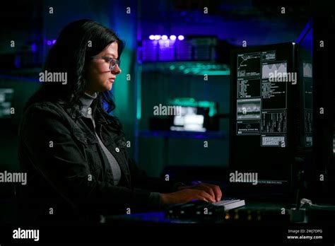 Low Key Lighting Shot Of Female Computer Hacker Sitting In Front Of