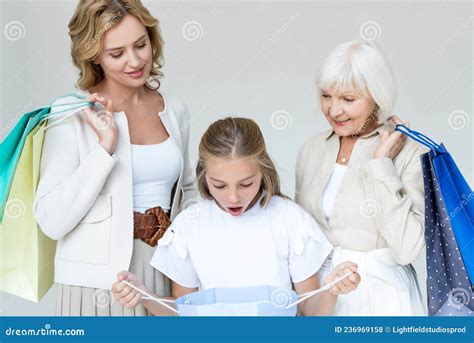 Granddaughter And Grandmother Folding Clean Clothes On A Shelf Of A