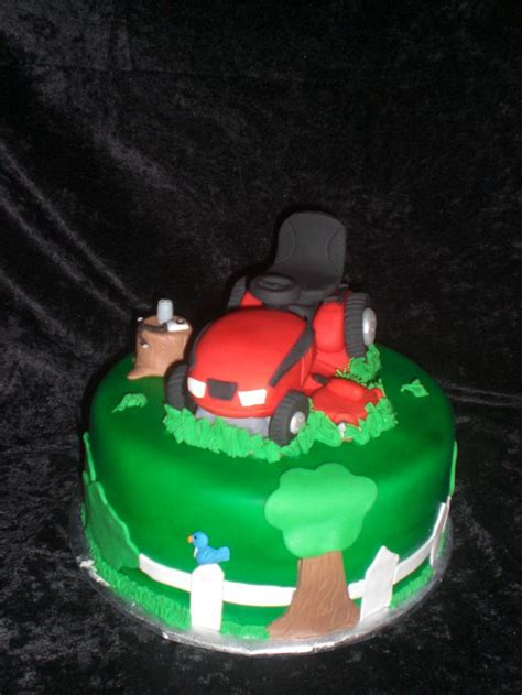 A Lawn Mower Cake On A Black Tableclothed Surface With Trees And Grass