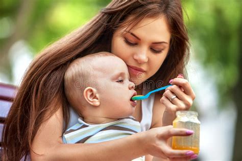 Cuchara De Alimentación Del Bebé De La Madre En El Parque Al Aire Libre
