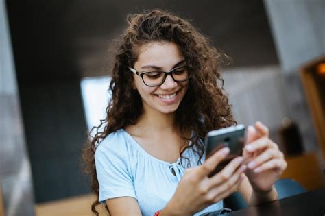 Premium Photo Smiling Woman Using Mobile Phone At Table
