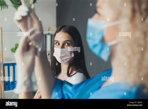 Nurse Preparing Syringe To Give Shot To A Scared Female Patient