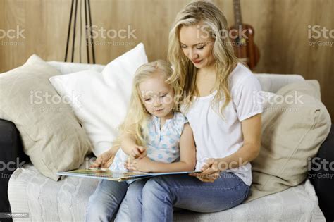 행복한 가족 금발의 젊은 어머니는 나무 바닥에 앉아있는 동안 그녀의 귀여운 딸에게 책을 읽고 모성 개념 2명에 대한 스톡 사진