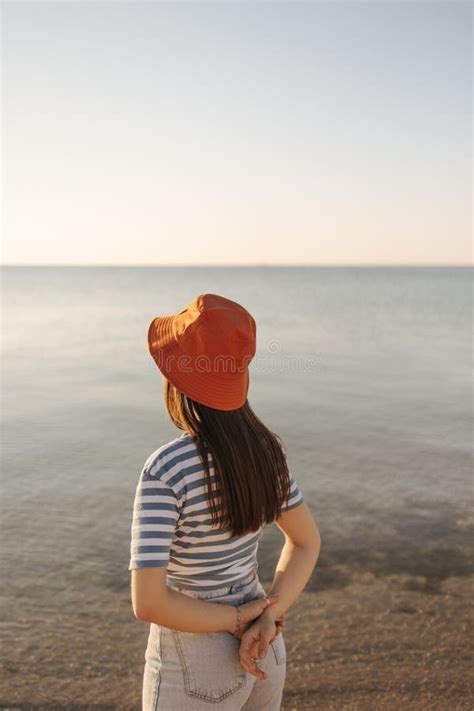 Beautiful Slender Fair Skinned Girl Stands On Shore Her Back To Camera
