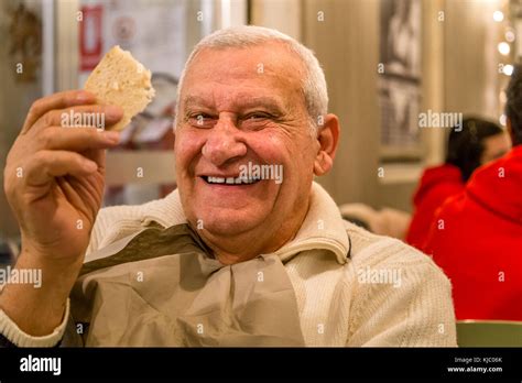Happy Old Man Smiling While Eating A Slice Of Bread In A Restaurant