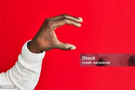 빨간색 고립 된 배경 따기와 보이지 않는 것을 복용 공간을 보여주는 손가락으로 개체를 들고 아프리카 계 미국인 흑인 젊은 남자의