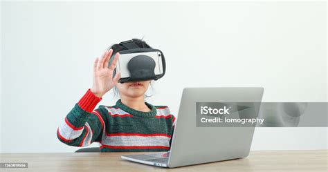 홈 안경의 책상에 앉아 Vr을 입은 어린 소녀는 가상 글로벌 인터넷 연결 메타버스 게임을 위한 Vr 헤드셋을 착용한 흰색 옷을