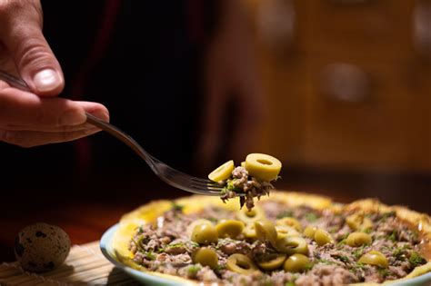 포크에 포크와 음식이 있는 손의 클로즈업 어두운 나무 배경에 메추라기 알을 곁들인 대나무 마키스에 참치와 올리브와 딜을 곁들인 팬케이크 0명에 대한 스톡 사진 및 기타