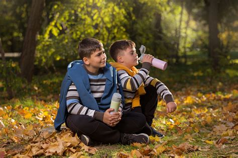 보온병을 가진 두 소년 가을 공원에서 게임과 산책 후 아름다운 햇빛 라이프 스타일과 함께 휴식을 취하십시오 10월에 대한 스톡