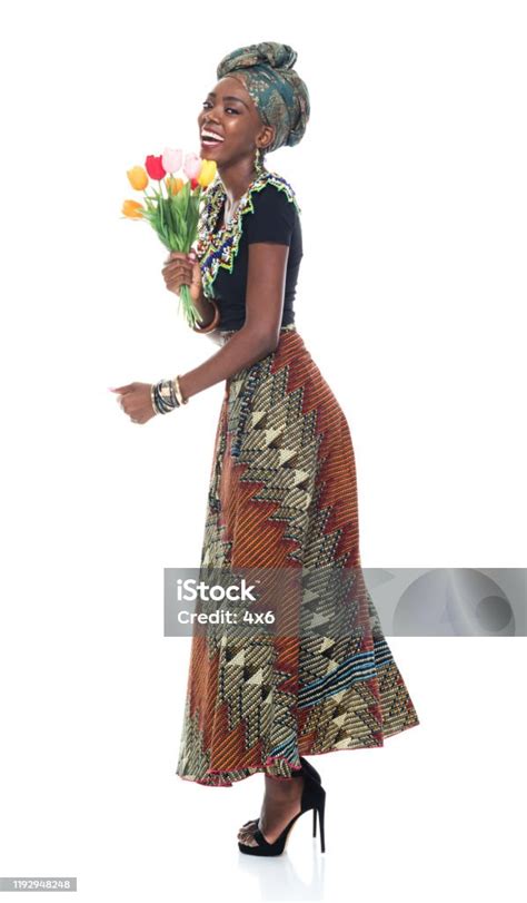 2029세의 아프리카 민족 아프리카계 민족 젊은 여성 머리 스카프 드레스 전통 의류를 입고 웃고 행복 쾌활 하 고 튤립 꽃을 들고 의외의 전체 길이 측면 보기 20 29세에