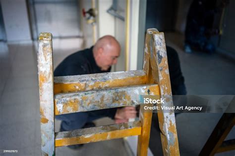 나무 계단은 전경에 초점을 맞추고 남성 화가는 배경 수평 Fixxer 상부 집 여전히 45 49세에 대한 스톡 사진 및 기타 이미지 45 49세 Diy 가사 집안일