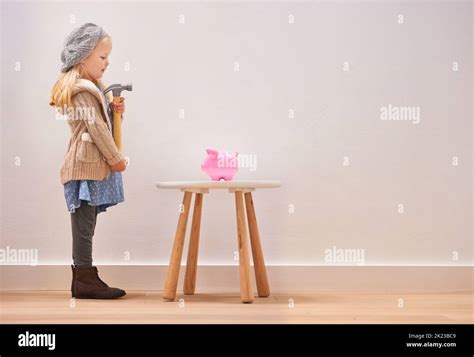 Pour Casser Ou Ne Pas Casser Une Petite Fille Debout Devant Sa Tirelire Avec Un Marteau Photo