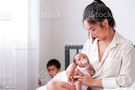아시아 의 어머니 수행 그녀의 신생아 에 무릎 과 앉아 에 침대 와 그녀의 아들 에 이 침실 가족에 대한 스톡 사진 및 기타