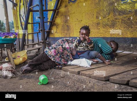 A Woman Takes A Nap Close By Her Daughter By The Streets In Kibera