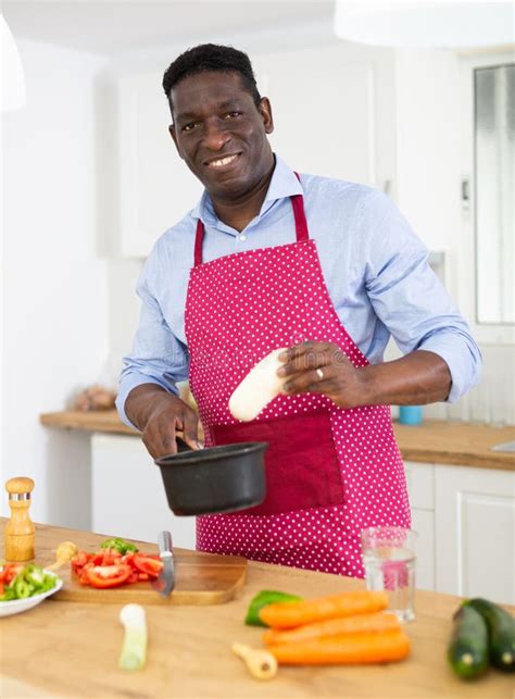 Man From America In An Apron Is Preparing To Cut Vegetables In The