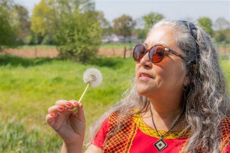 Brunette Latin American Woman Wearing Sunglasses Looking At Dandelion