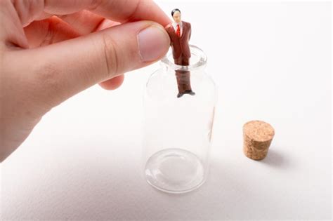 Premium Photo Hand Putting Tiny Figurine Of Man Model In Bottle