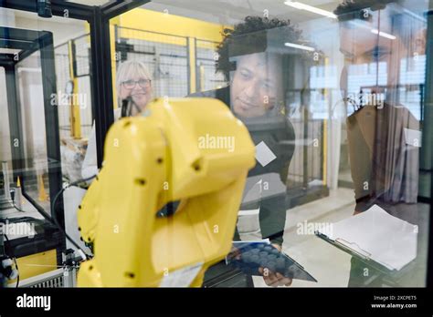Team Of Engineers Working Together To Program And Inspect A Robotic Arm
