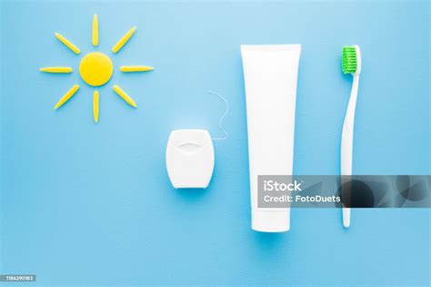 녹색 칫솔모 치약의 흰색 튜브 파스텔 블루 배경에 치실이있는 칫솔 노란색 태양 모양입니다 건강한 치아 아침 위생 개념 근접 촬영