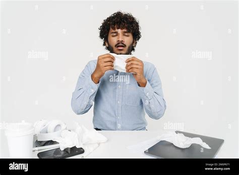 Young Indian Office Employee Is Sneezing By Office Table Over Grey