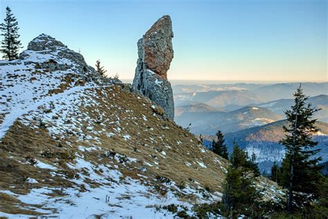 의인화 된 외관을 가진 자연 암석 절벽 안개가 자욱한 계곡과 언덕이 많은 풍경 배경 위의 산 꼭대기에 홀로 서 있습니다 극적인 겨울 풍경 조감도 0명에 대한 스톡 사진 및