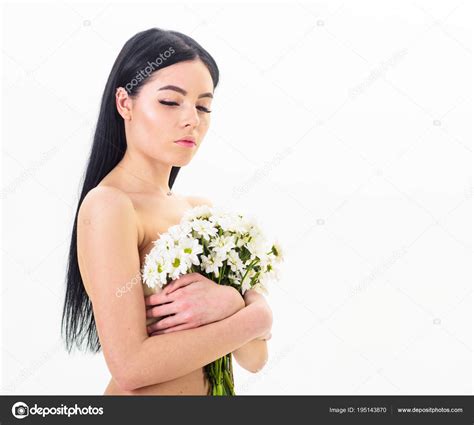 Señora cubre los pechos con flores aislado en blanco Mujer